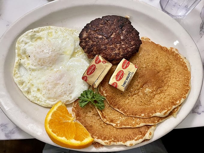 The holy trinity of breakfast: perfectly cooked eggs, golden pancakes, and a sausage patty that means serious business.