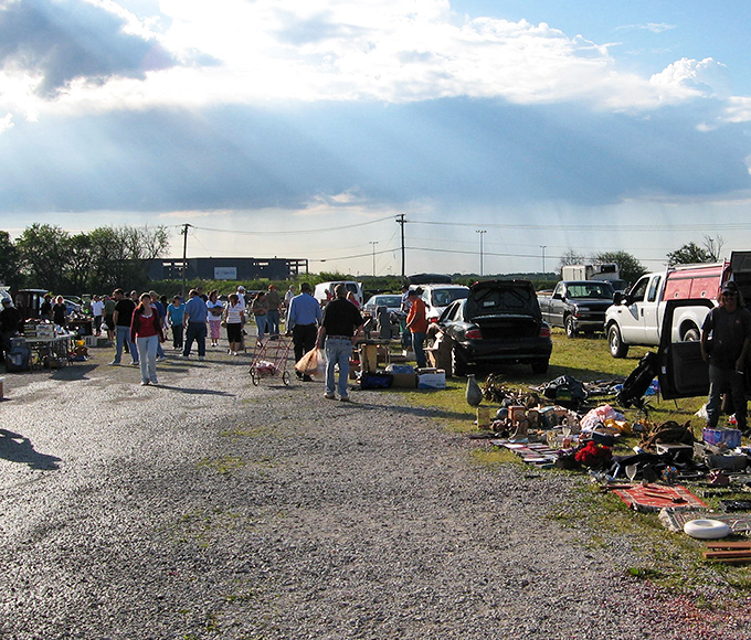 Sunbeams break through clouds as weekend warriors navigate the treasure-filled aisles, each carrying hope in shopping bags and carts.