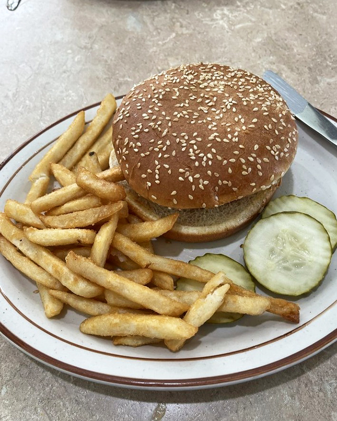 A proper diner burger demands respect—and both hands. The sesame-studded bun stands ready for the first magnificent bite.