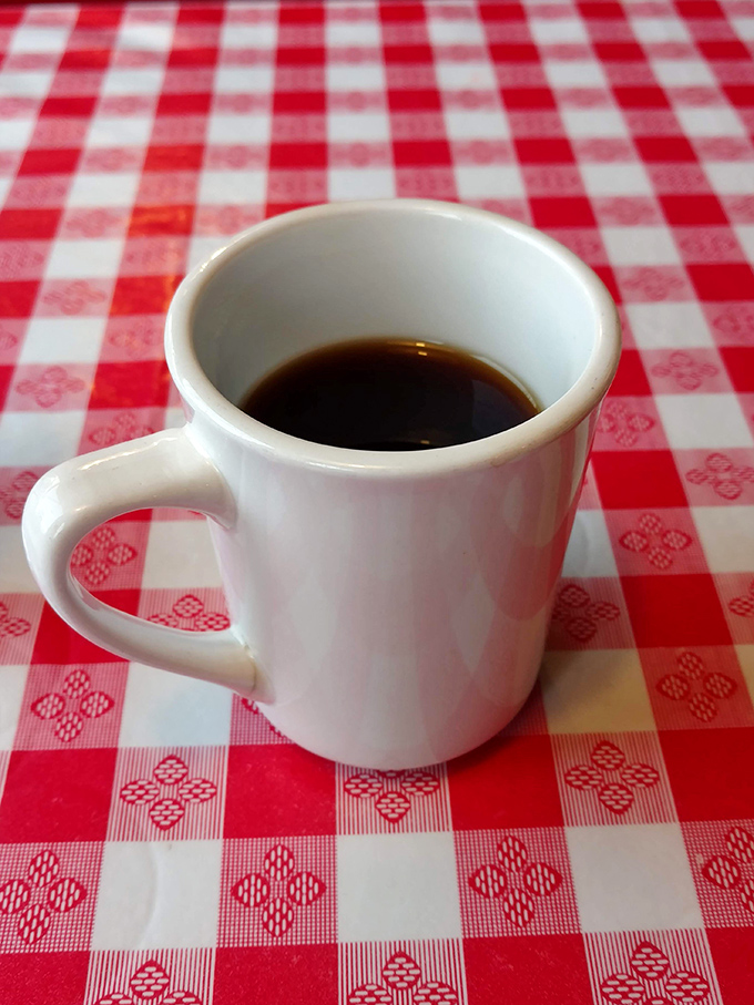 The humble white mug on checkered tablecloth &ndash; where coffee isn't just a beverage, but the lifeblood of diner culture and morning conversations.