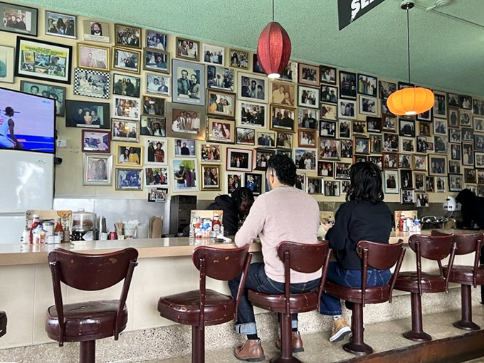 The counter seating offers front-row tickets to the breakfast show, with the wall of memories serving as the most authentic backdrop.