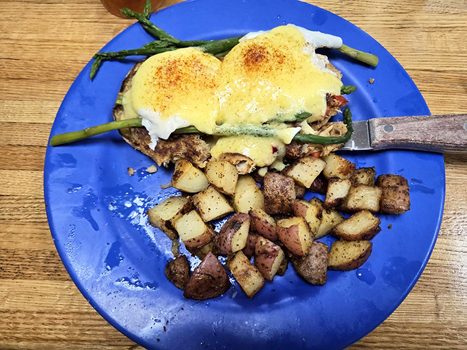 Crabcake Benedict on a blue plate—where coastal cuisine meets breakfast indulgence. Those home fries look like they've been studying the art of crispiness for decades.