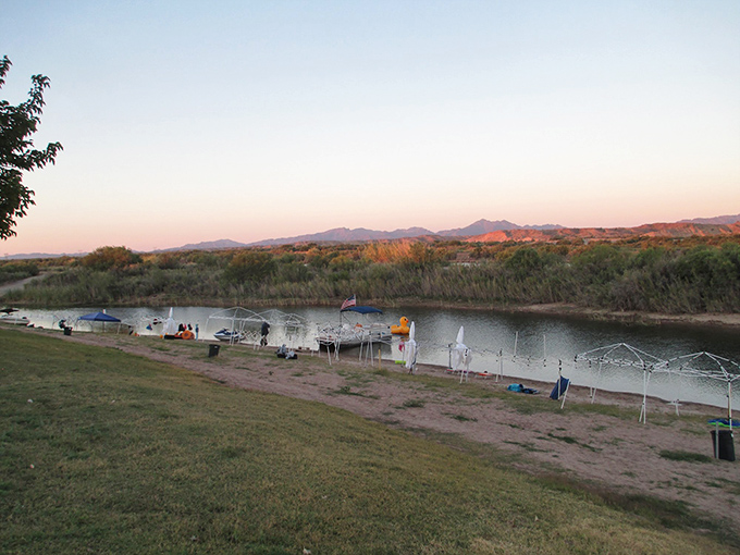 Sunset at the river's edge paints the water gold while campers settle in. This isn't camping &ndash; it's front-row seating to nature's nightly light show.