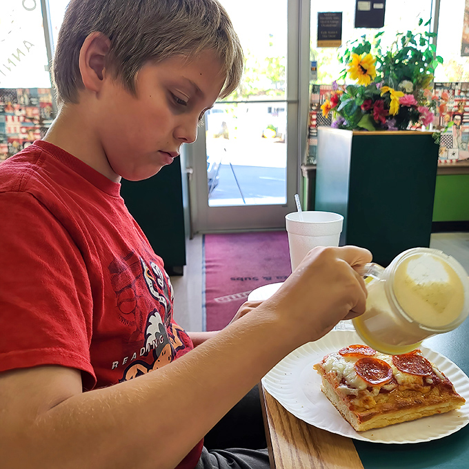 Young connoisseur demonstrates the proper pizza appreciation technique &ndash; pure concentration and unbridled joy in every bite.