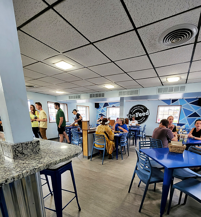 A bustling dining room where strangers become neighbors over great food. The blue chairs aren't just furniture&mdash;they're invitations.