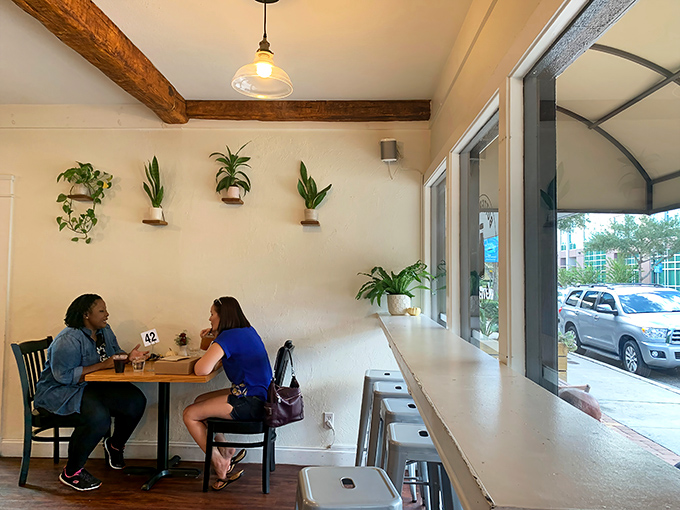 Two friends sharing coffee and conversation&mdash;the universal language of bakeries everywhere. Those wall-mounted plants are silently photosynthesizing all the gossip.