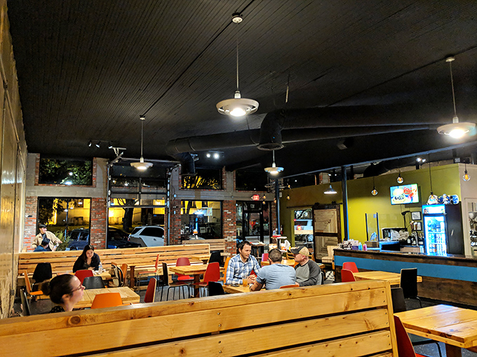 Where strangers become temporary tablemates in the shared pursuit of exceptional food, all bathed in the warm glow of pendant lights against exposed brick.