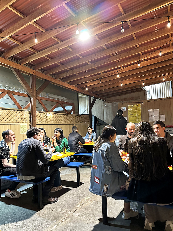 Under string lights and wooden beams, strangers become comrades united by the universal language of "this is so good I can't talk right now."
