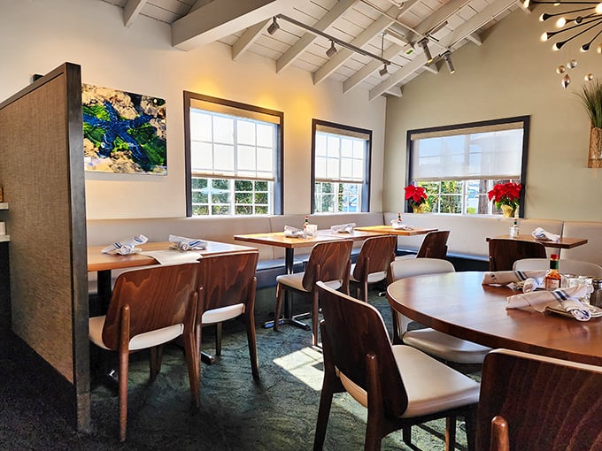 Sunlight streams through windows in this dining area, where mid-century modern meets maritime in perfect harmony.