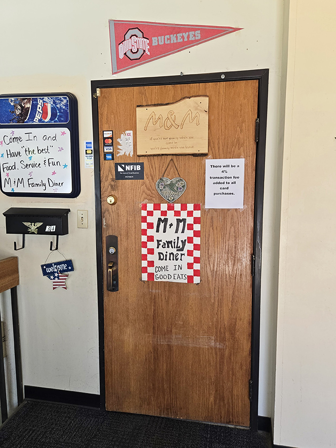The entrance door, adorned with Ohio State pride and checkered M&M signage, promises "GOOD EATS" with the confidence of someone who knows they're right.
