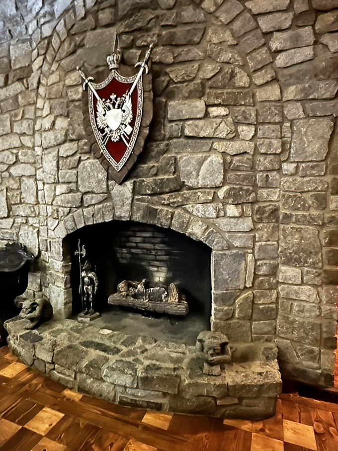 A massive stone fireplace anchors the room with rustic grandeur. Nothing says "medieval comfort" like a roaring fire beneath a heraldic shield.