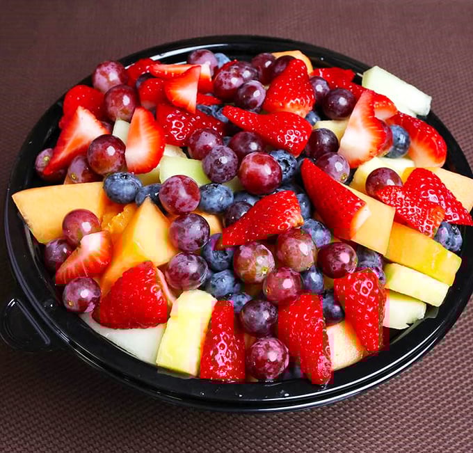 A vibrant fruit salad offers a refreshing counterpoint to the savory menu stars&mdash;proof that balance exists even in cheesesteak paradise.