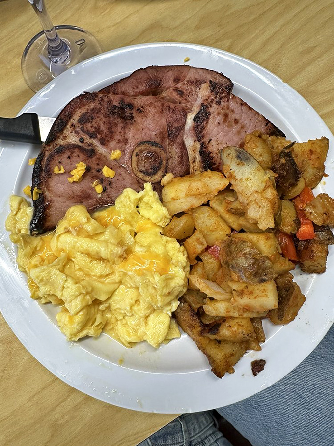 A breakfast plate that means business: ham steak, cheesy scrambled eggs, and home fries seasoned to wake up your taste buds.