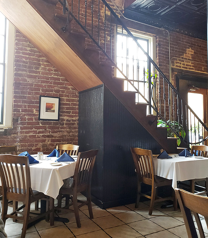 Wooden stairs lead to culinary adventures above, while brick walls whisper stories of meals shared and wine glasses clinked through the decades.