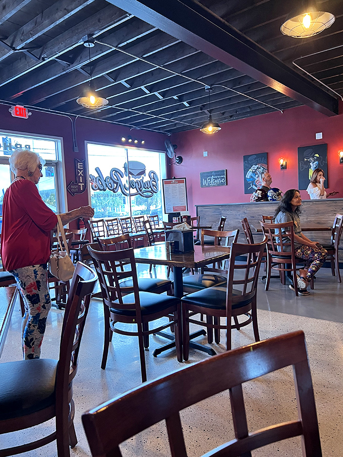 Modern lighting fixtures illuminate the temple of smashed burger goodness. The red walls practically pulse with flavor anticipation.
