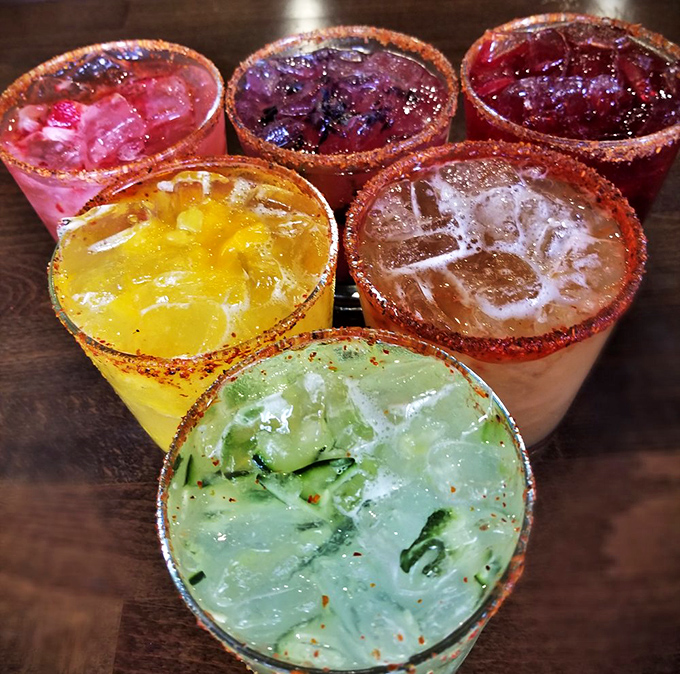 A rainbow of margaritas with rims dressed better than most people at formal events. Liquid vacation in six different colors.