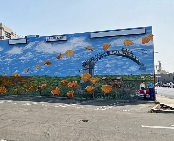 The iconic Modesto Arch mural captures the city's agricultural heritage and famous "Water Wealth Contentment Health" motto against a backdrop of California poppies.