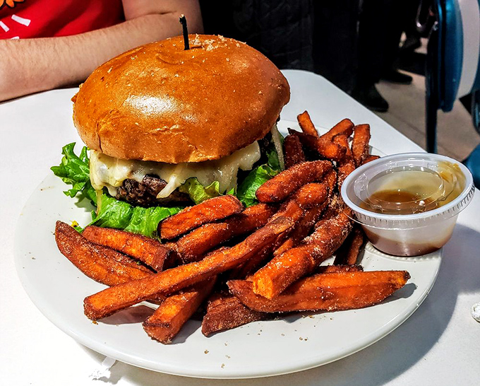 Sweet potato fries escort a burger that's dressed better than most people at the mall. A meal that demands to be photographed.