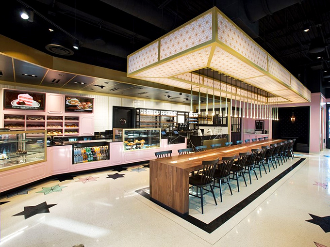 The sleek counter seating offers front-row tickets to the pastry show, where display cases showcase sweet protagonists waiting for their moment in the spotlight.