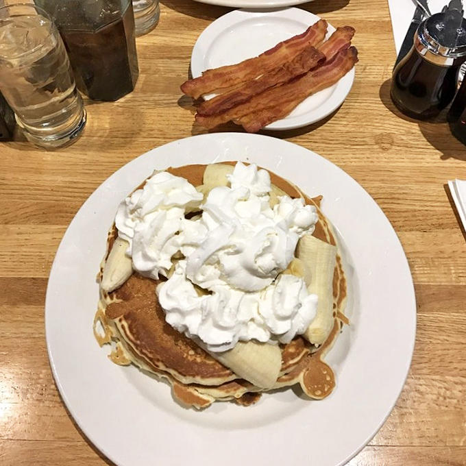 Pancakes stacked higher than your weekend expectations, crowned with a cloud of whipped cream and fresh bananas—breakfast nirvana has been achieved.