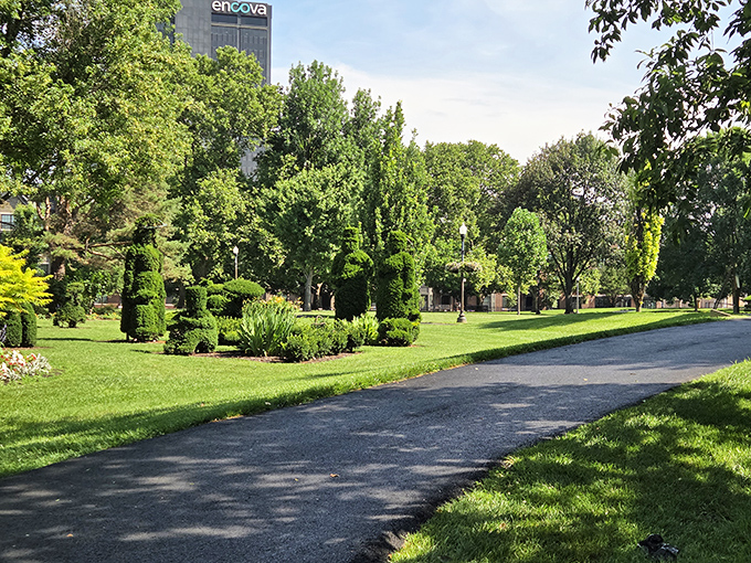 Winding paths invite exploration through this green gallery, where city skyline meets sculptural shrubs in perfect urban harmony.