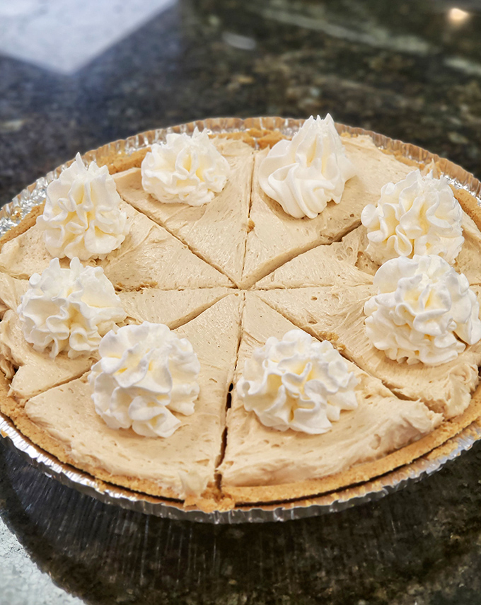 Peanut butter pie with whipped cream dollops standing at attention. The kind of dessert that makes you consider ordering a second slice first. 