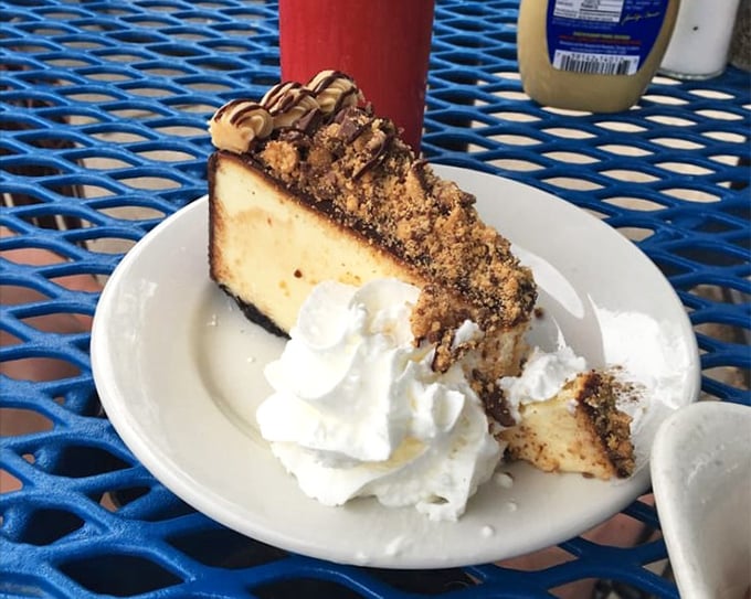 A slice of cheesecake that makes diets weep with jealousy. The whipped cream isn't decoration—it's the exclamation point on a dessert declaration.