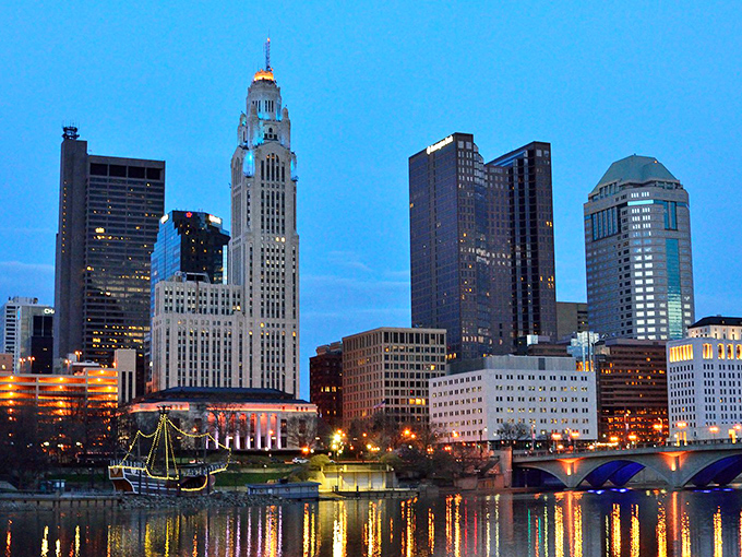 Columbus's skyline glows at dusk, reflecting in the Scioto River. A reminder that urban adventures await just a short drive from Circleville's peaceful streets.