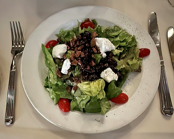 A simple greens salad becomes a canvas of flavors with bright tomatoes and generous crumbles of cheese &ndash; proof that sometimes less truly is more.
