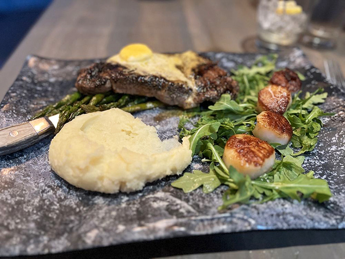 Land meets sea in perfect harmony. Perfectly seared steak and scallops with mashed potatoes create a surf-and-turf symphony on slate.