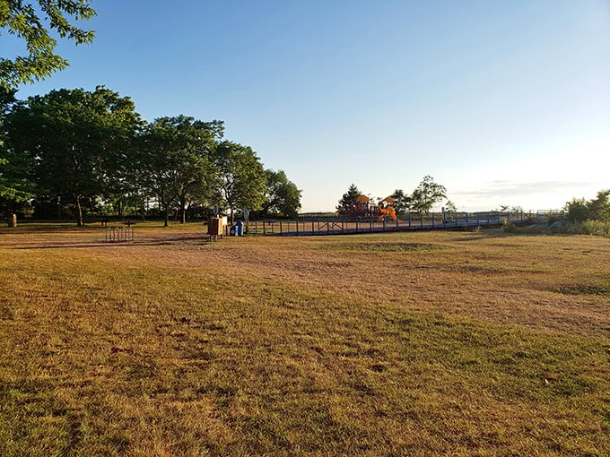 Golden hour transforms this simple park into a postcard-worthy scene, where open space meets the promise of lakeside adventure.