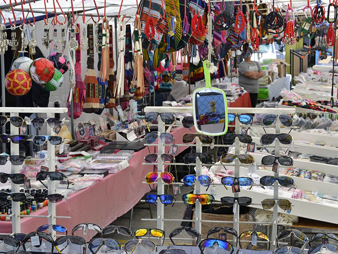 Sunglasses and accessories dangle like modern jewelry in a bazaar, each pair promising to transform you into someone slightly more interesting.