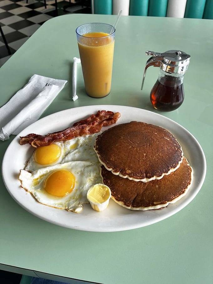 The breakfast trinity: golden pancakes, sunny eggs, and bacon that's achieved the perfect crisp. Orange juice standing by for moral support.
