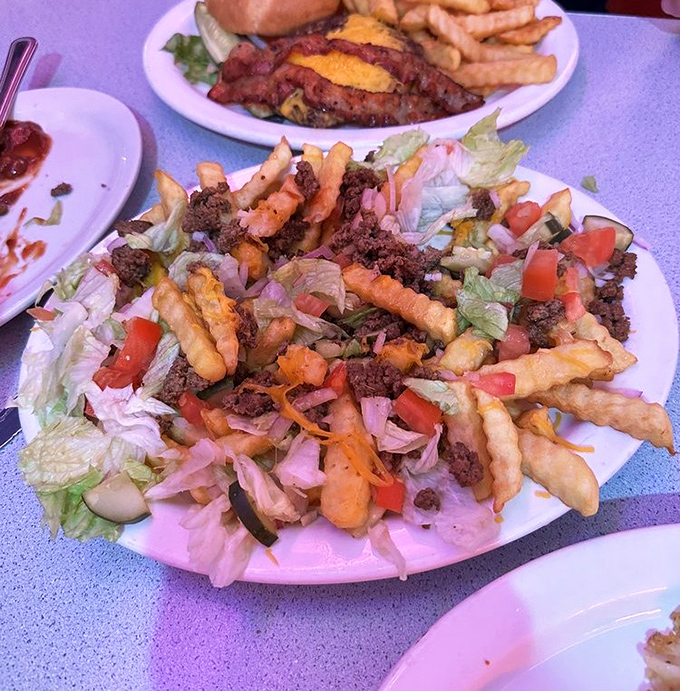 A mountain of fries topped with savory meat and fresh veggies&mdash;proof that sometimes the best culinary experiences don't require fancy silverware.