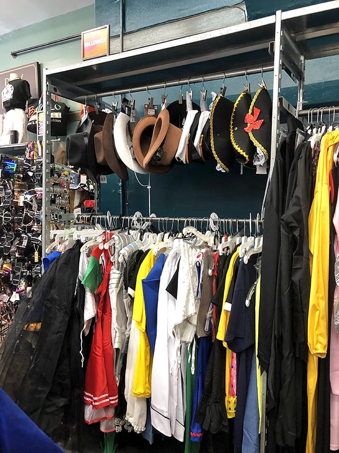 The hat collection hangs like possibilities, from cowboy dreams to festival-ready statements above a rainbow of recycled fashion.