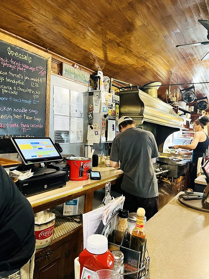 Behind the counter, organized chaos creates perfect meals while maintaining that authentic diner energy and community spirit.