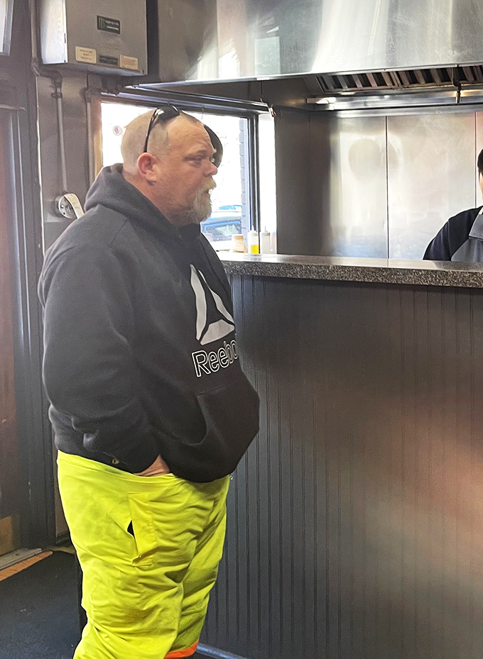 A customer awaits his order, displaying the universal body language of someone who knows good food is worth the wait.