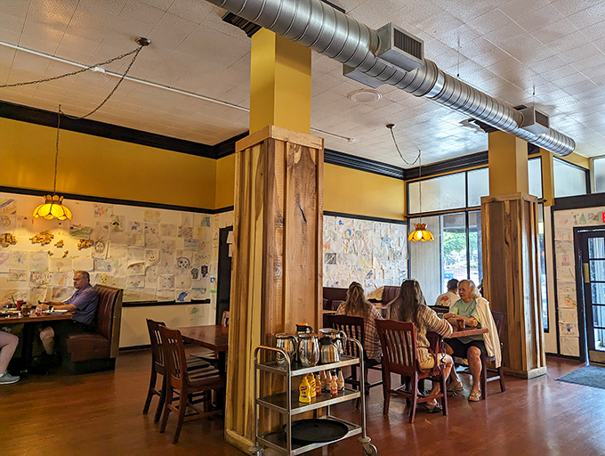 Yellow walls and wooden columns create distinct dining areas where conversations flow as freely as the coffee refills.