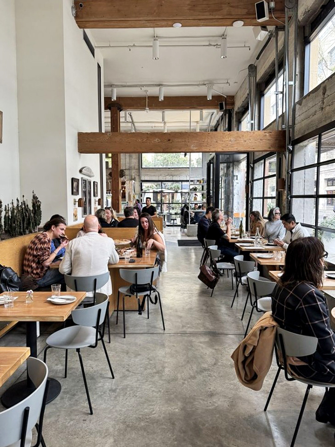 Diners lost in conversation and contemplation under soaring wooden beams. Pizza has a way of bringing people together better than any social media platform.