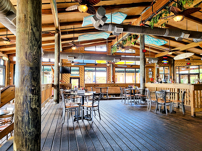 Weathered wooden posts support a ceiling where surfboards and plants hang like treasured artifacts in this cathedral of casual coastal dining.