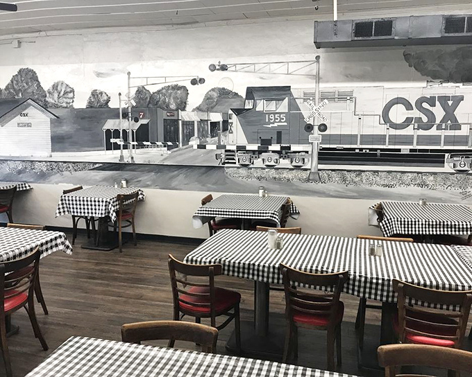 The train mural watches over diners like a benevolent spirit, while red chairs add pops of color to the nostalgic black-and-white scheme.