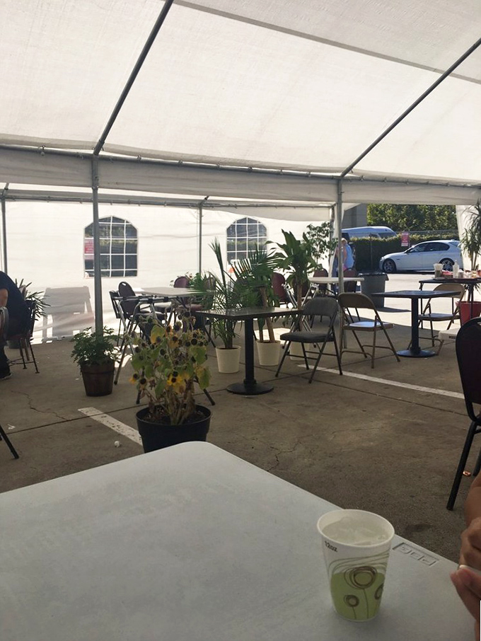 The outdoor tent setup brings a touch of casual charm. Sunflowers in pots add a cheerful note to this practical pandemic-era dining solution.