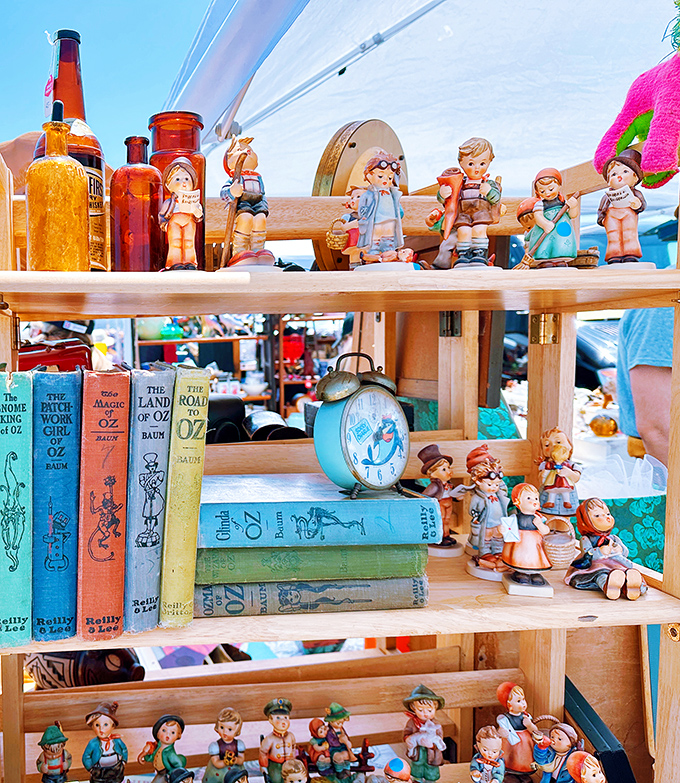 A nostalgic lineup of vintage Hummel-style figurines stands at attention beside colorful Wizard of Oz books&mdash;childhood memories for sale, no batteries required.