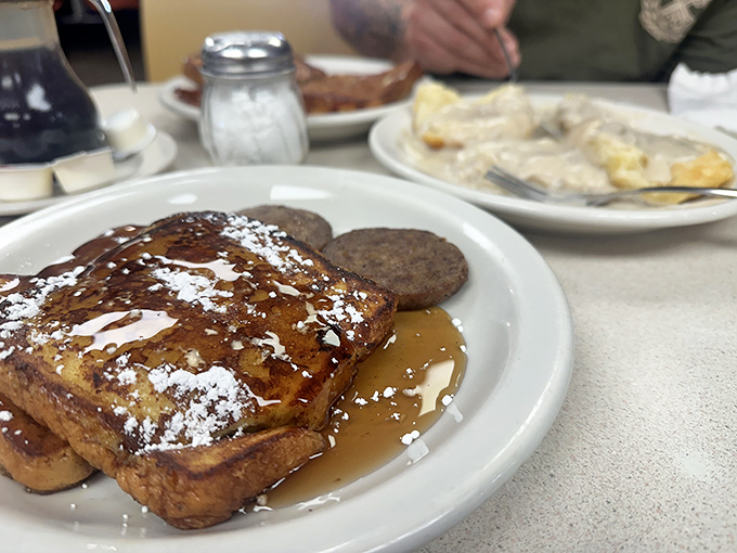 French toast dusted with powdered sugar, dripping with syrup, and accompanied by sausage patties&mdash;breakfast's greatest hits on a single plate.
