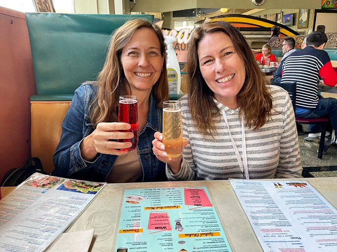 Two friends raising glasses in the universal toast that says, "We made an excellent decision coming here today." Cheers to that!