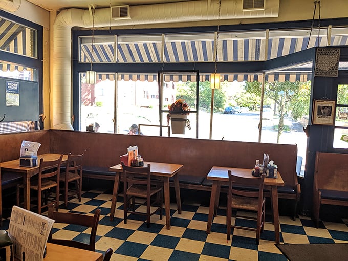 The blue-striped awnings continue inside, where sunlight streams through windows illuminating booths that have hosted generations of ice cream enthusiasts.