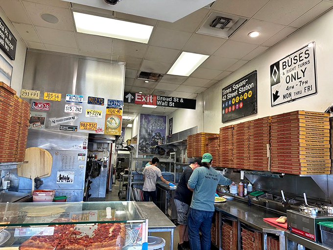 Behind the counter, pizza boxes stack like edible skyscrapers ready for their delicious destiny.