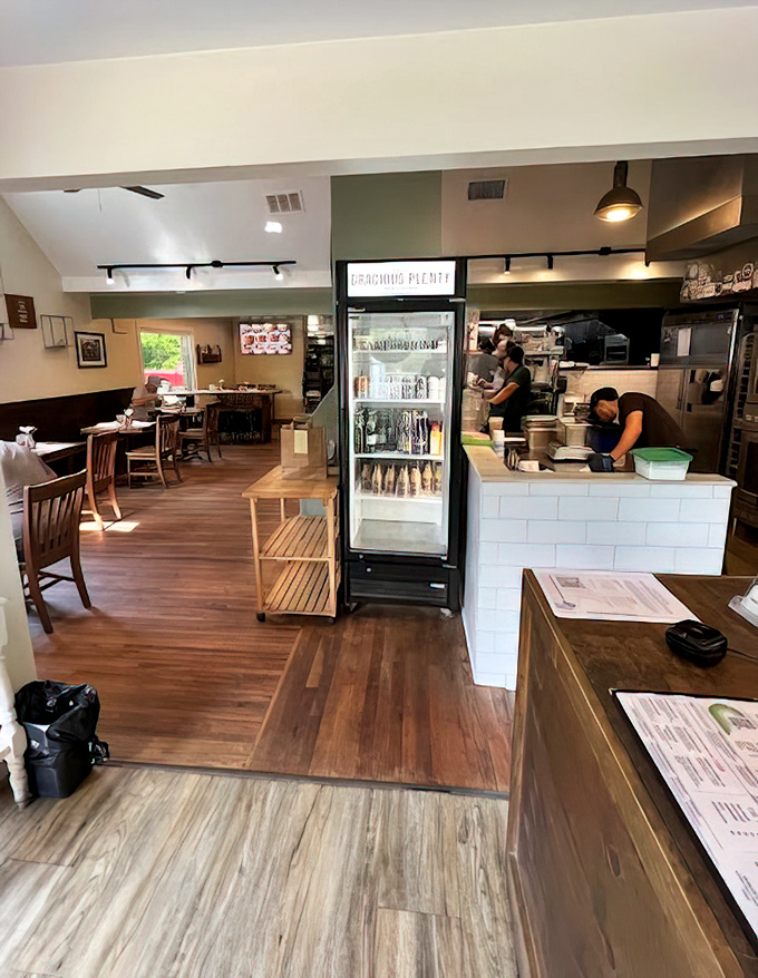 Sunlight streams through windows onto wooden tables while the open kitchen buzzes with activity—breakfast theater at its finest.