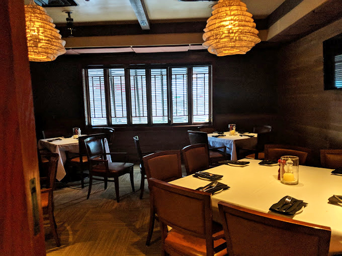 Private dining areas offer intimate spaces for conversation, where the woven pendant lights cast the kind of glow that makes everyone look like movie stars.