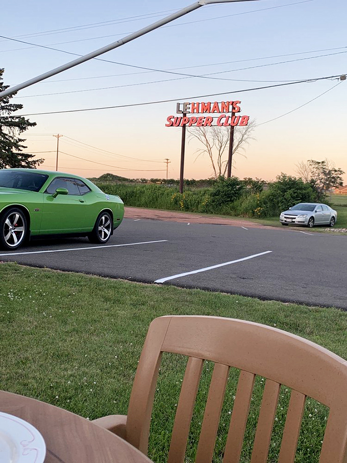 The parking lot view at dusk, where muscle cars meet family sedans, all united by their drivers' excellent taste in dinner destinations.